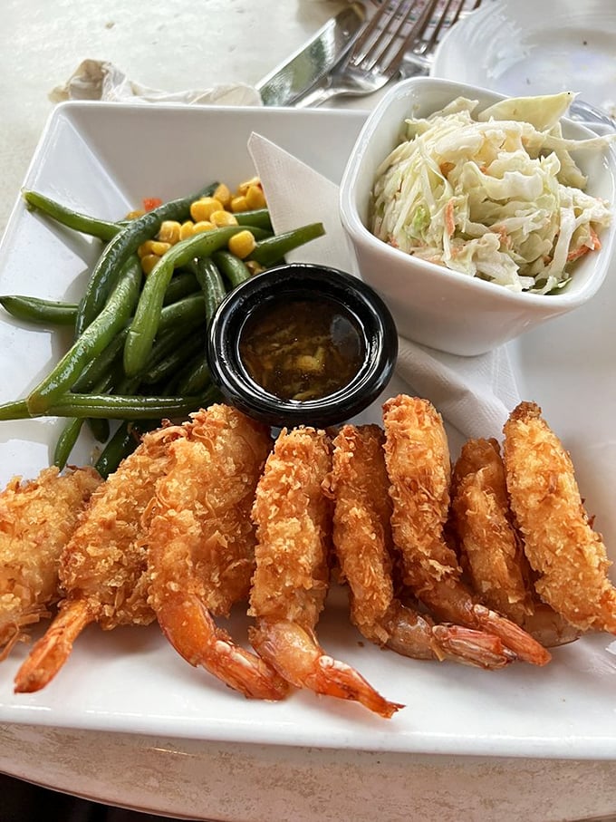 Crispy coconut shrimp lined up like delicious soldiers, accompanied by fresh green beans, sweet corn, and house-made coleslaw—a Florida beach meal that demands no apologies.
