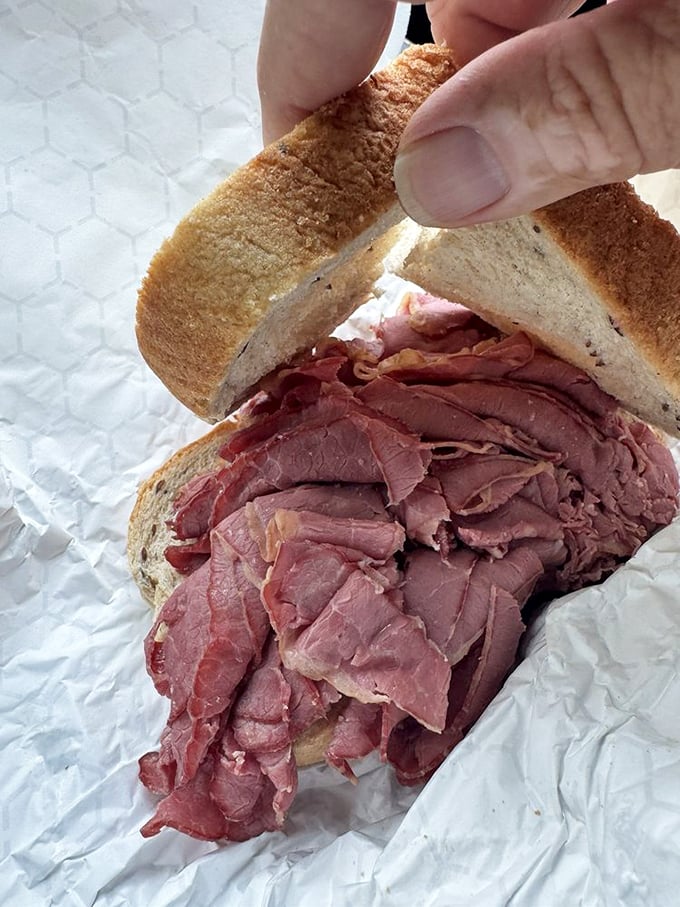 Corned beef piled high enough to require structural engineering, served with the mandatory pickle accomplice.