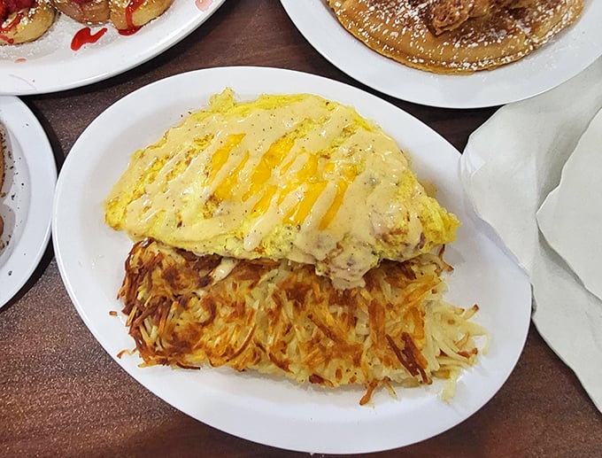 This omelet doesn't just sit on the plate—it commands it, with hash browns crisped to the exact point where potato meets magic.