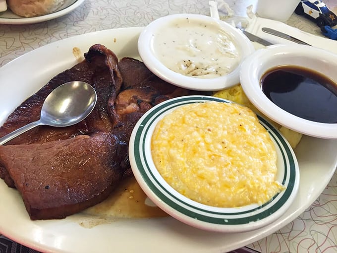 Country ham with that deep mahogany color that signals real-deal curing, alongside creamy grits and pepper-flecked gravy. Breakfast of champions, Southern style.
