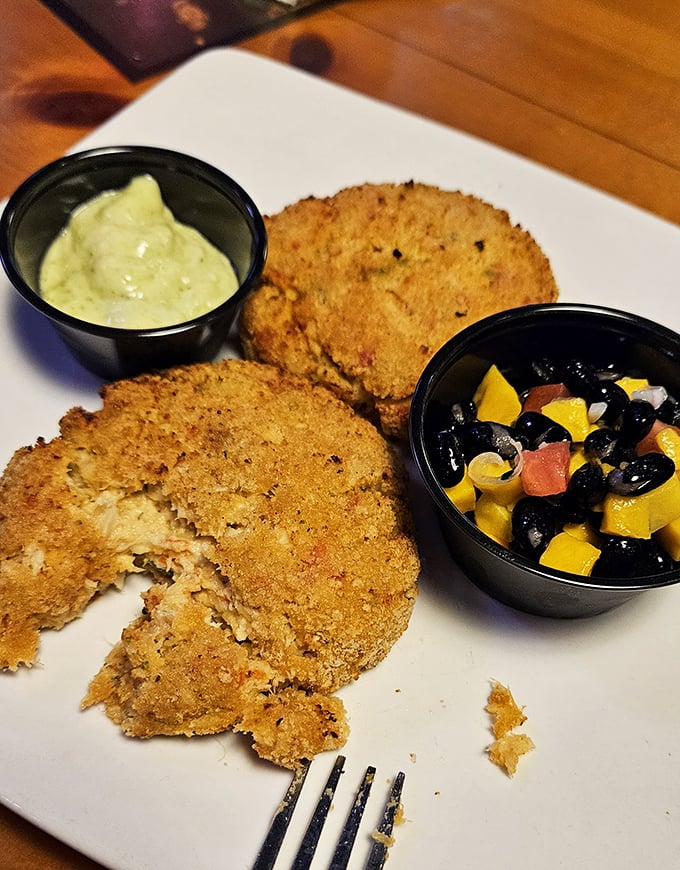Golden-crusted crab cakes with a vibrant mango-black bean salsa—proof that sometimes the best seafood doesn't swim to your plate, it struts.