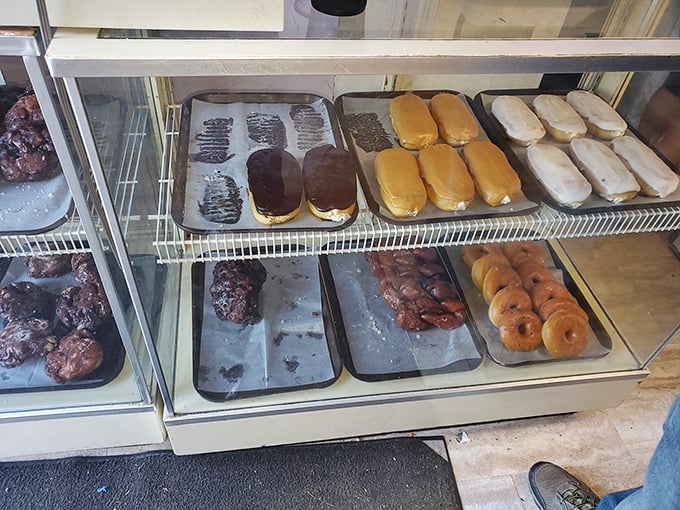 Long-lost cousins of the donut family reunited in one display case. Those chocolate-topped eclairs are practically waving at you.