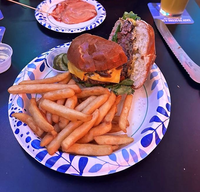 The burger arrives like a celebrity making an entrance—complete with golden fries standing at attention, ready to escort each bite to flavor town.
