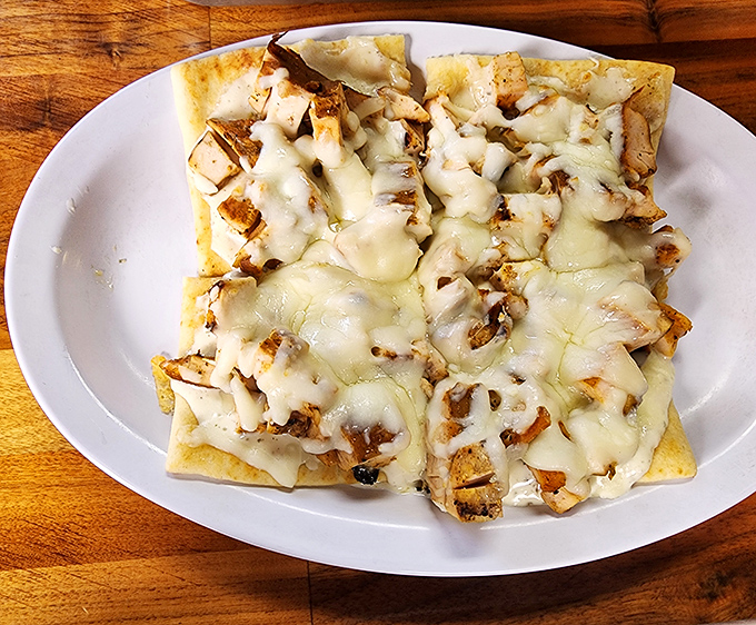 This flatbread isn't trying to be fancy – it's just honest-to-goodness BBQ chicken melted under a blanket of cheese that stretches for days.