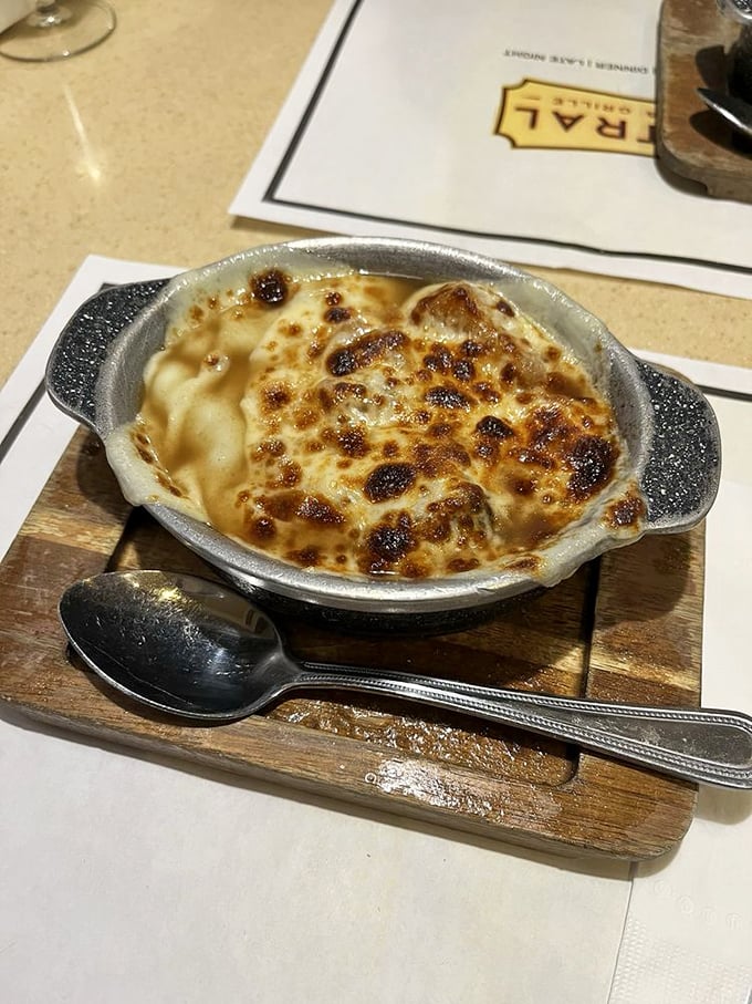 Bubbling cheese creates a golden canopy over this French onion soup. The spoon waits patiently for you to break through to the treasure below.