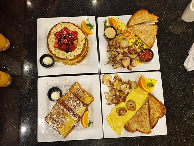 The breakfast quartet in perfect harmony – golden pancakes topped with fresh fruit, French toast dusted with powdered sugar, and eggs cooked just right.