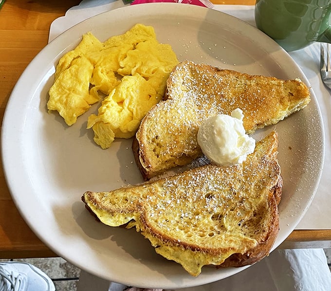Golden French toast dusted with powdered sugar alongside fluffy scrambled eggs—proof that sometimes the simplest pleasures are the most profound.