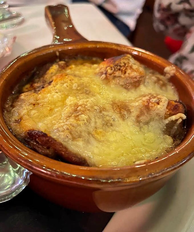 Bubbling cheese stretching skyward like it's trying to high-five your taste buds. This French onion soup isn't just comfort food—it's a warm hug in a crock.