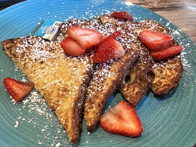 French toast that's achieved celebrity status—golden-brown, dusted with powdered sugar, and adorned with strawberries like little red jewels of morning happiness.