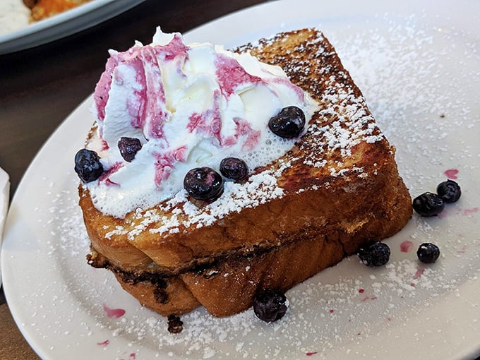 French toast that's gone to finishing school – crisp edges, custardy center, and topped with berries and cream that make breakfast feel like dessert.