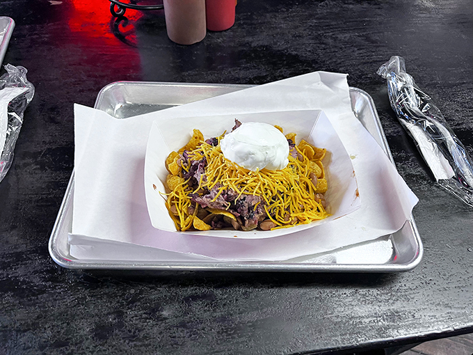Frito Pie—where corn chips meet barbecue in a marriage blessed by the gods of comfort food. Topped with cheese and sour cream because why stop at merely delicious?
