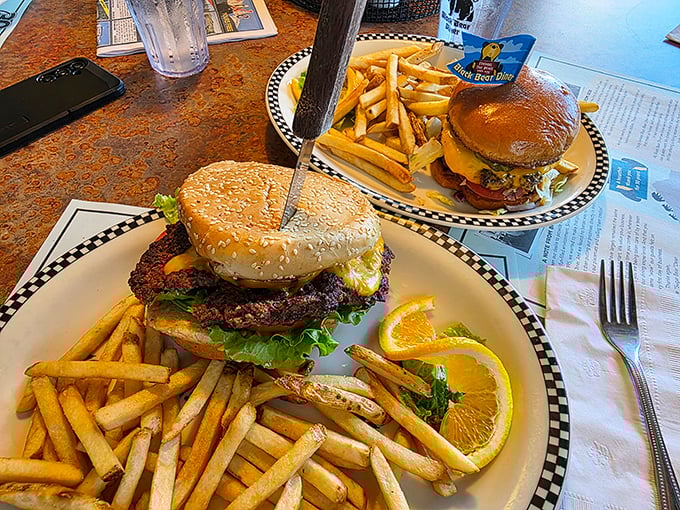 These burgers don't just satisfy hunger—they conquer it. Served with a mountain of golden fries and that signature checkered plate rim.