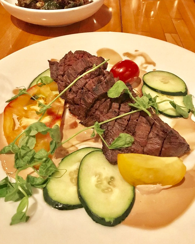 This hanger steak isn't just cooked—it's respected. Perfectly sliced, surrounded by fresh vegetables, it's the bovine equivalent of a standing ovation.