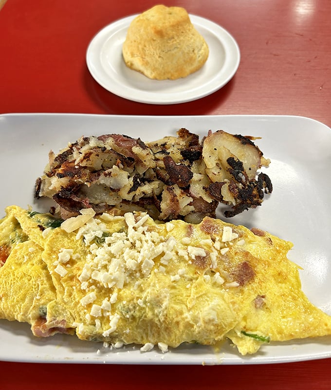 A golden-brown biscuit stands sentinel over a perfect omelet and crispy potatoes – the breakfast trinity that launches a thousand good days.
