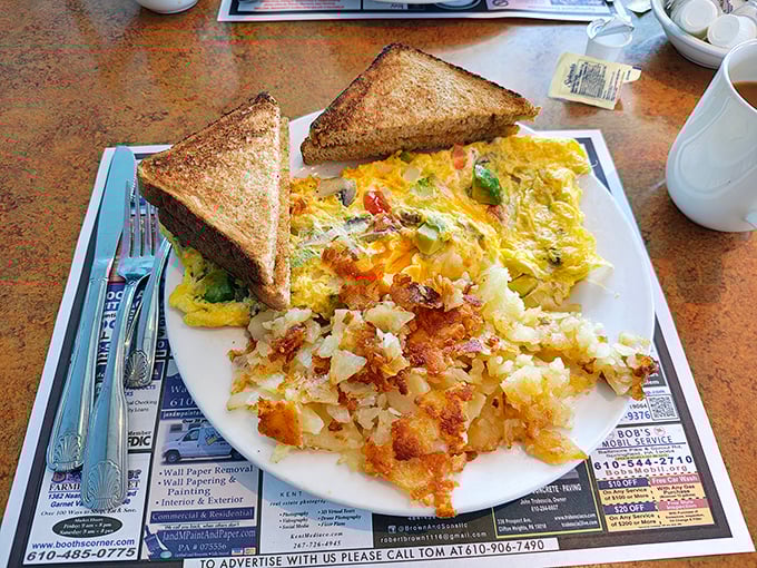 Breakfast nirvana: a veggie-packed omelet alongside crispy home fries and perfectly toasted bread—the holy trinity of morning satisfaction.