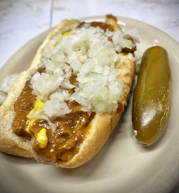 The Detroit Coney in its natural habitat—a snappy dog nestled in a steamed bun, blanketed with meaty chili, diced onions, and that essential streak of mustard.