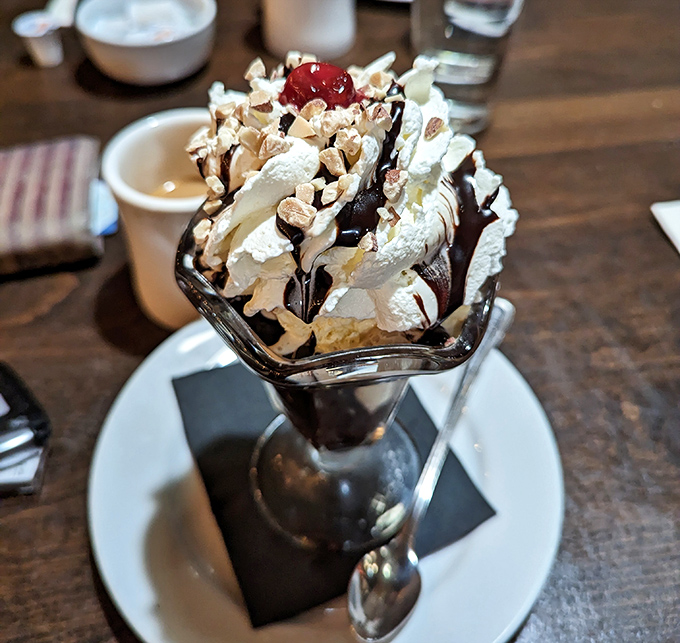 This hot fudge sundae isn't just dessert, it's architecture – a towering achievement of ice cream, whipped cream, and nuts that demands both respect and a spoon.