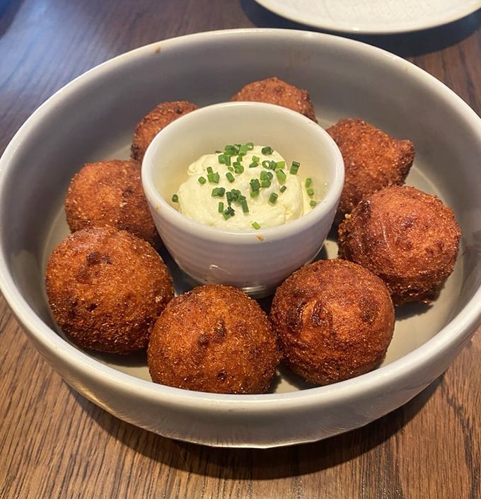 These Southern-style hush puppies aren't playing games – golden-brown spheres of happiness surrounding a creamy dip that demands to be savored.