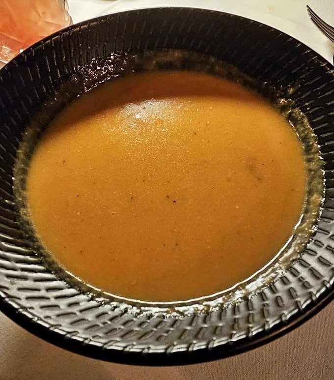 This isn't just soup—it's liquid gold. The lobster bisque's velvety texture and rich amber color hint at the oceanic treasures within.