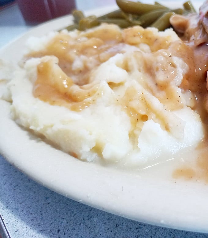 These mashed potatoes aren't just a side dish – they're a cloud-like vessel for rivers of homestyle gravy that demands to be savored.