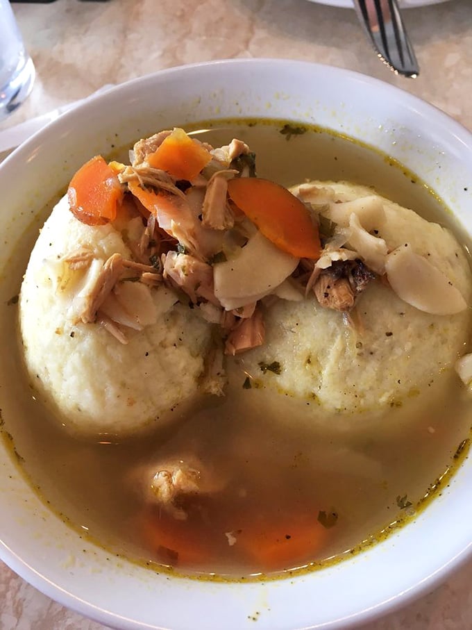 Matzo ball soup that could heal whatever ails you—two fluffy dumplings floating in golden broth like edible life preservers.