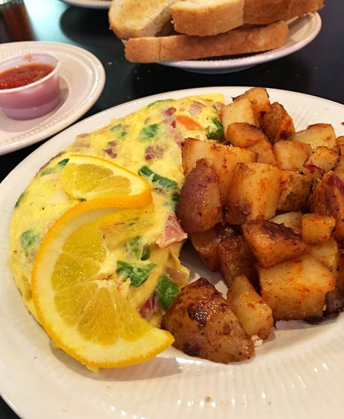 This isn't just any omelet—it's breakfast alchemy. Ham and veggies folded into fluffy eggs with home fries that could make a potato farmer weep with pride.