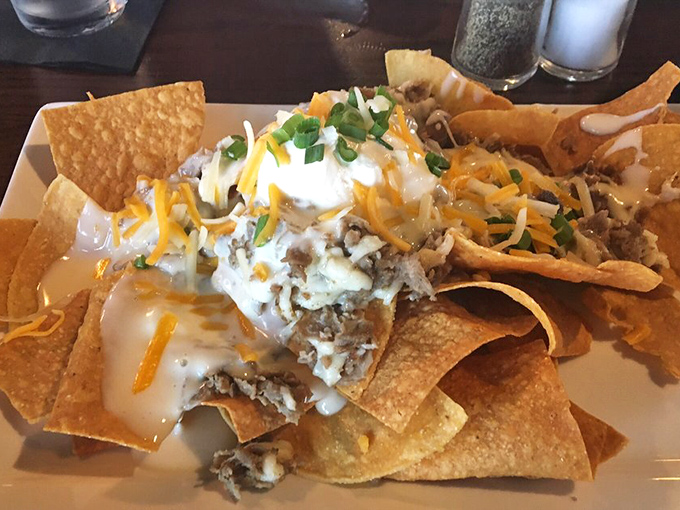 Nachos that don't mess around—a mountain of chips supporting an avalanche of toppings that requires strategic eating and possibly a game plan.
