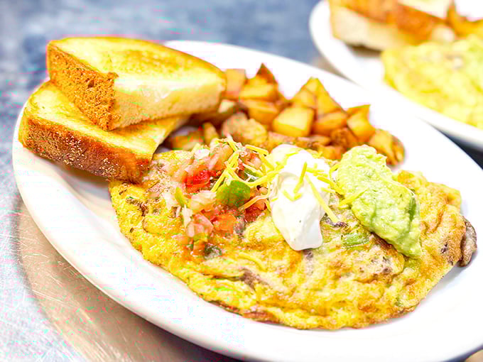 This isn't just an omelet; it's a fluffy yellow canvas painted with fresh vegetables and topped with the holy trinity: sour cream, pico, and avocado.