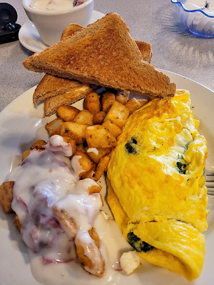 Breakfast harmony achieved: a fluffy omelet, perfectly crisped home fries, and toast—the holy trinity of morning satisfaction.