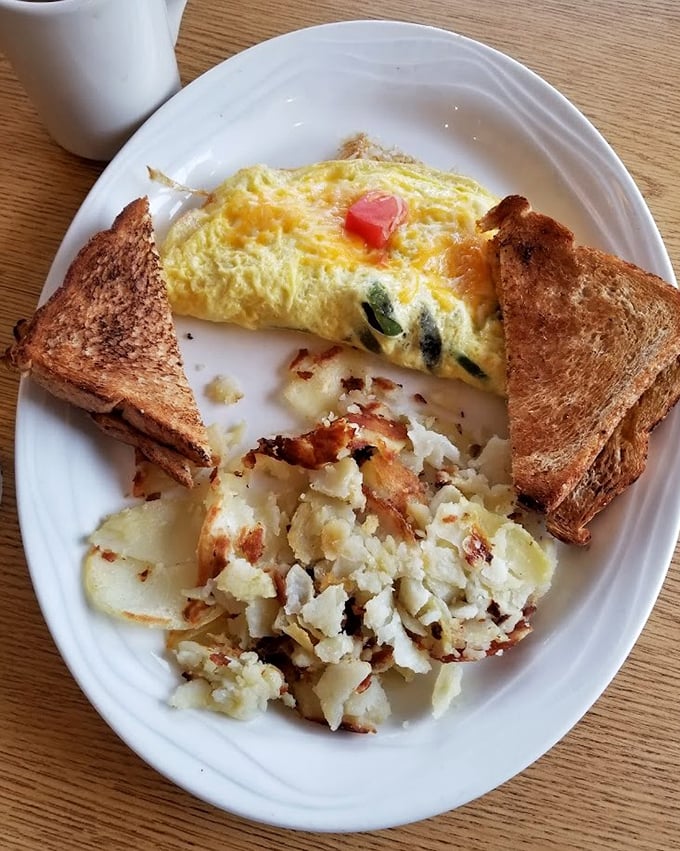 This omelet doesn't just sit on the plate—it commands attention with melted cheese and perfectly crisped potatoes standing guard.