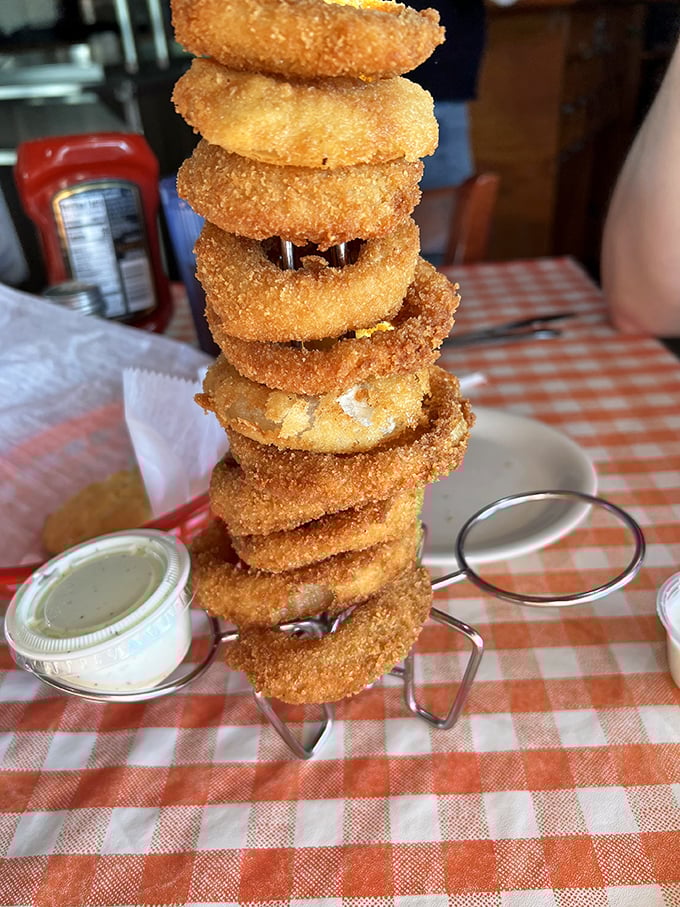 These aren't just onion rings – they're crispy golden halos stacked like the world's most delicious Jenga game. The dipping sauce is liquid gold.