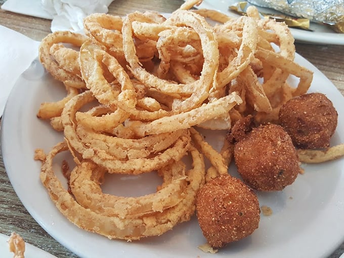 Onion rings and hush puppies sharing a plate like old friends—crispy, golden companions that make you wonder why vegetables ever bothered growing any other way.