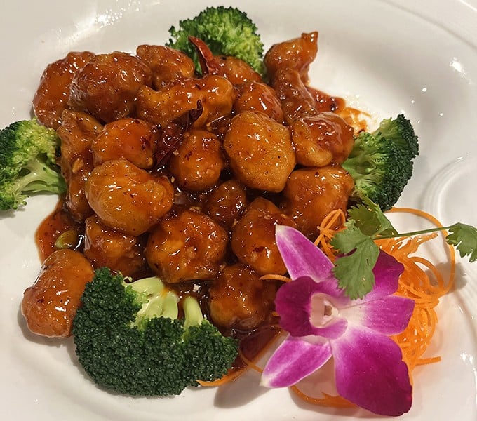 Orange Chicken that actually tastes like oranges—what a concept! Crispy, tangy, and adorned with an orchid that's basically saying, "You're welcome."