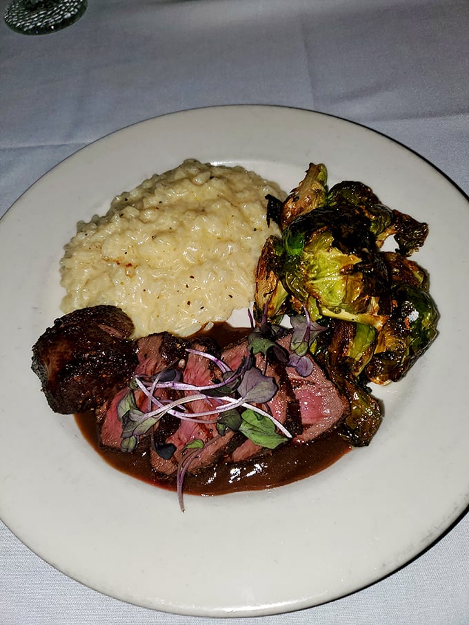 Perfectly seared elk medallions nestled against creamy risotto and charred Brussels sprouts—proof that frontier food has come a long way since jerky.