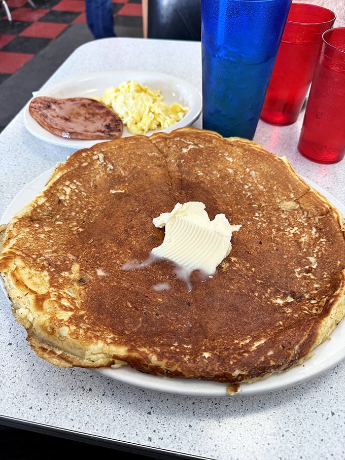 The pancake that ate Waterloo—a golden-brown masterpiece large enough to have its own zip code, with butter melting into a perfect puddle of possibility.
