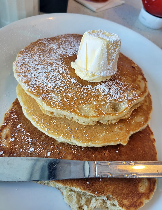 These pancakes aren't just breakfast, they're an engineering marvel—fluffy platforms perfectly designed to support that glorious butter crown and powdered sugar snowfall.