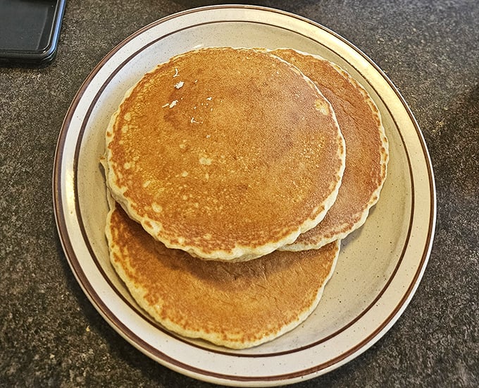 Golden pancakes that look like they've been practicing for their food magazine photoshoot – fluffy, perfectly round, and ready for their maple syrup bath.