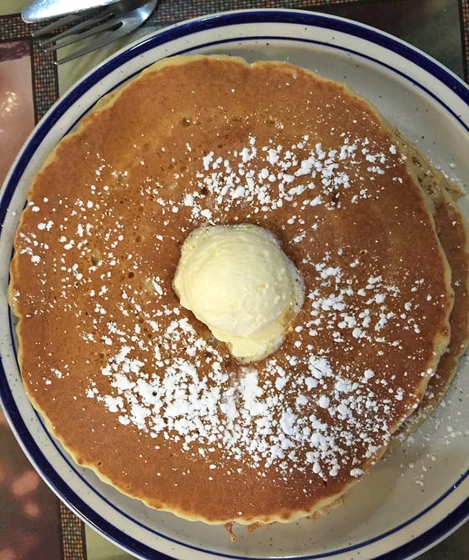 This isn't just a pancake—it's a golden canvas of possibility, dusted with powdered sugar and crowned with a melting butter throne.