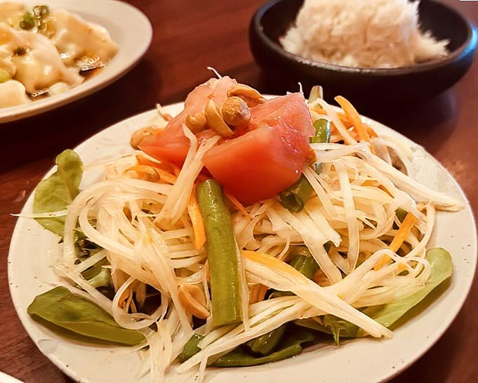 A papaya salad that dances between sweet, sour, and spicy – like a perfectly choreographed flavor ballet on a pristine white plate.