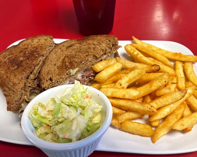 This isn't just a sandwich, it's edible nostalgia – a perfectly grilled patty melt with crispy fries and coleslaw that would make your grandmother proud.