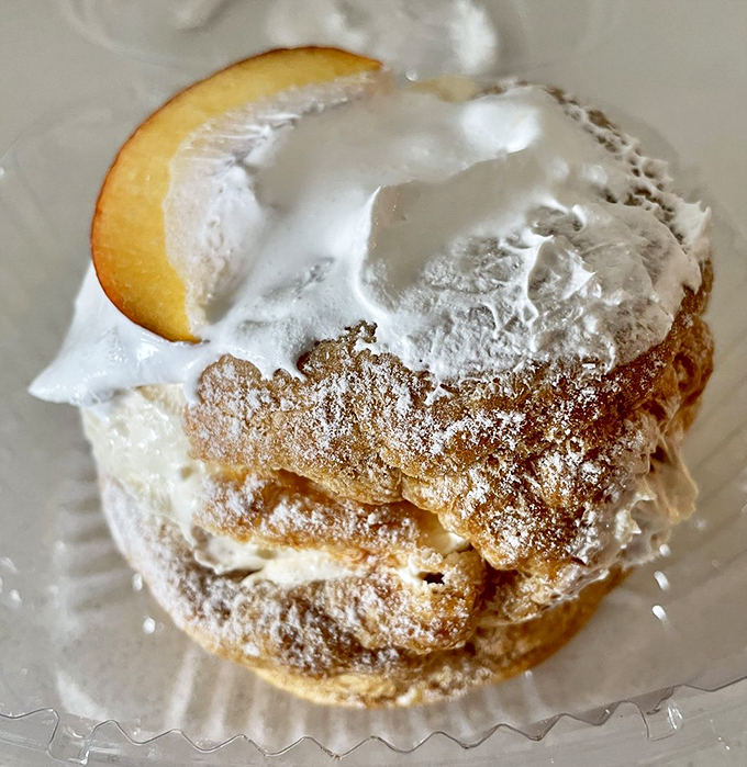 The famous cream puff in its natural habitat—a masterpiece of pastry engineering that makes you wonder why all desserts aren't this ambitious.