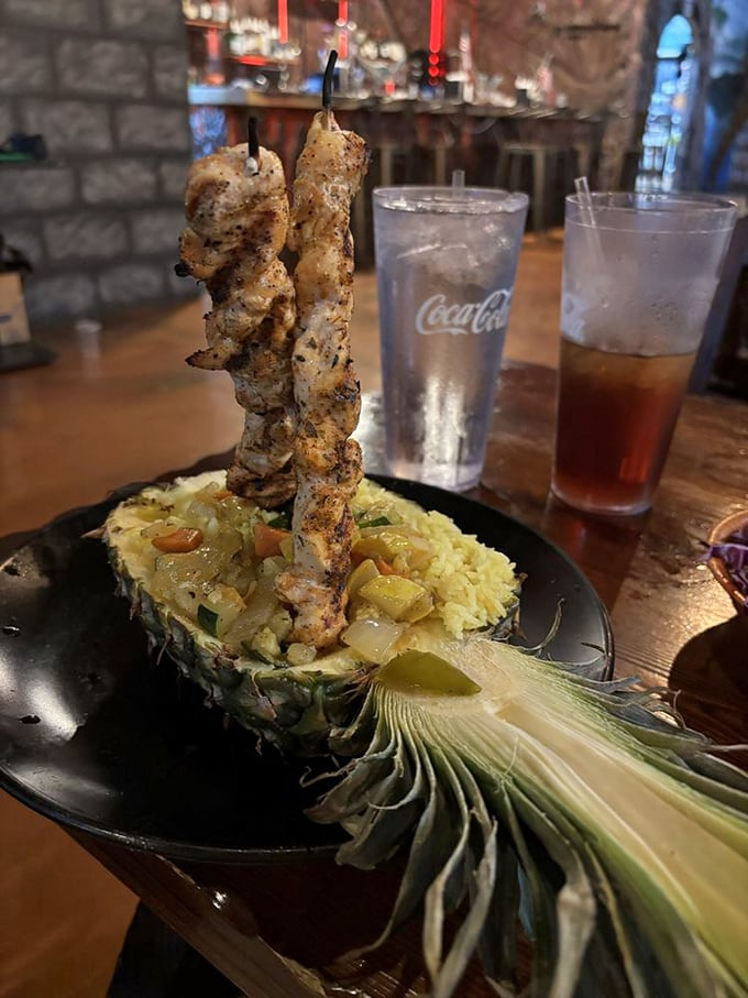Skewered chicken served in a hollowed pineapple boat – because regular plates are for restaurants without dinosaurs on the roof.
