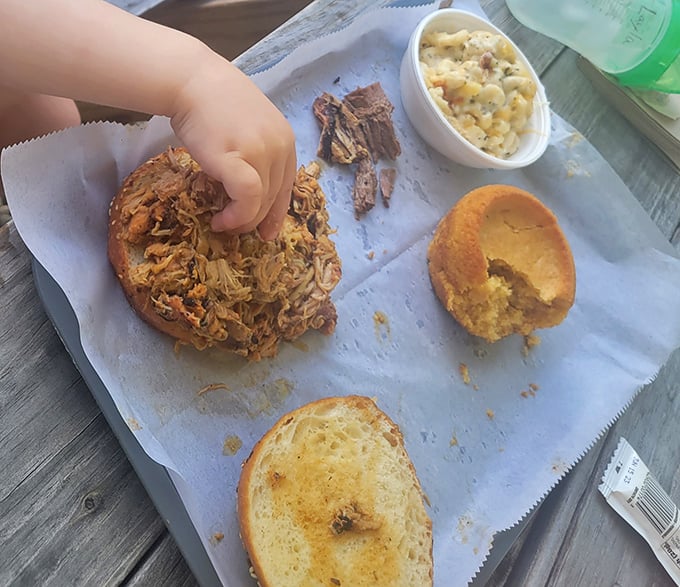 Someone's about to experience the joy of pulled meat on fresh bread with creamy mac 'n cheese—a happiness that transcends all age groups.