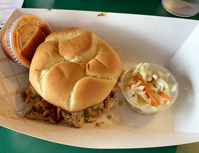 The pulled chicken sandwich sits proudly on its throne, flanked by loyal subjects of coleslaw and sauce—a humble monarch of lunch options.