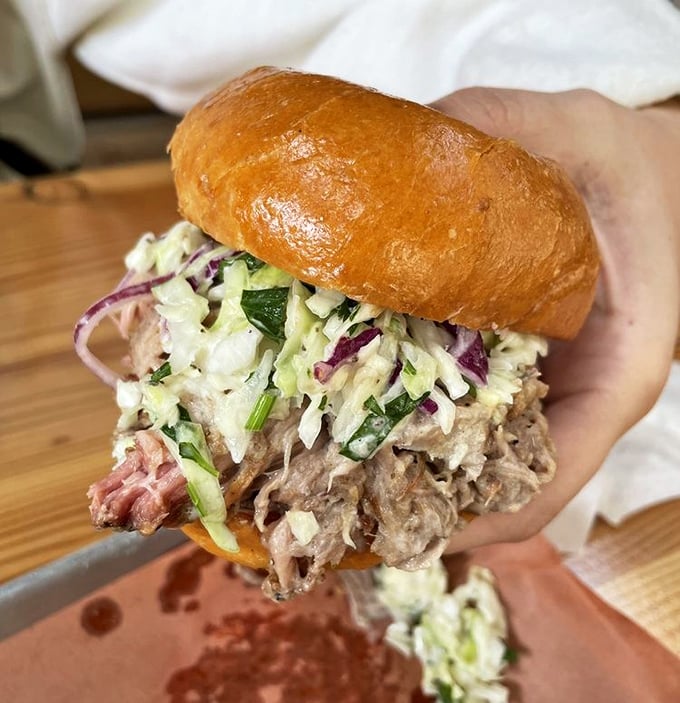 This pulled pork sandwich isn't just a meal, it's an event – tender strands of smoky pork crowned with fresh slaw on a pillowy bun.