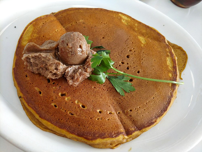 This pumpkin pancake isn't just breakfast—it's autumn on a plate, complete with a scoop of what appears to be cinnamon butter melting into pancake perfection.