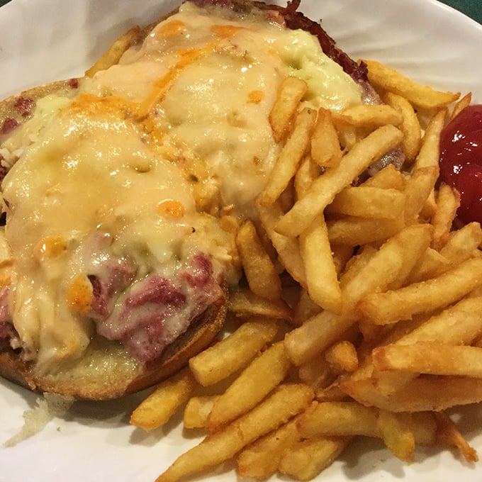 The Reuben sandwich—where melted cheese cascades over corned beef like a dairy waterfall, with fries standing by for the aftermath.