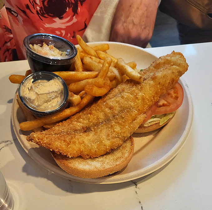 The rockfish sandwich—Maryland's answer to coastal cuisine—arrives golden and crispy, flanked by fries and house-made sauces that demand to be sampled.