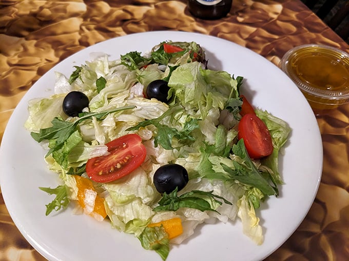 Fresh greens, ripe tomatoes, and black olives create a salad that's anything but an afterthought here.