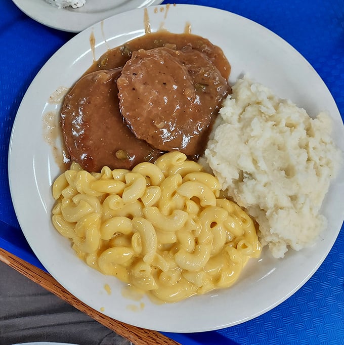 Comfort on a plate: tender Salisbury steak swimming in rich gravy alongside creamy mashed potatoes and mac and cheese that could make a grown adult weep.